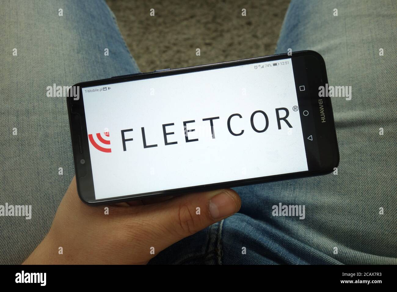 Man holding smartphone with FleetCor Technologies, Inc. company logo ...