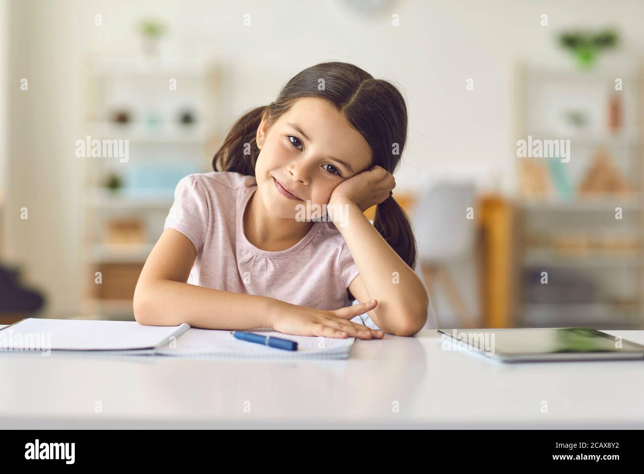 Online. Girl child looks at the camera of the gadget online sitting ...