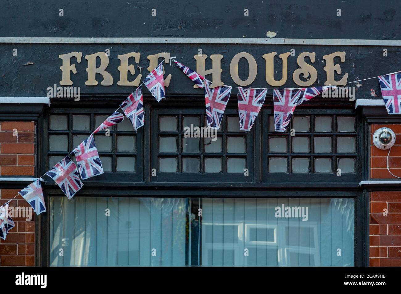 A Free House sign on the exterior of a british pub with Union jack ...