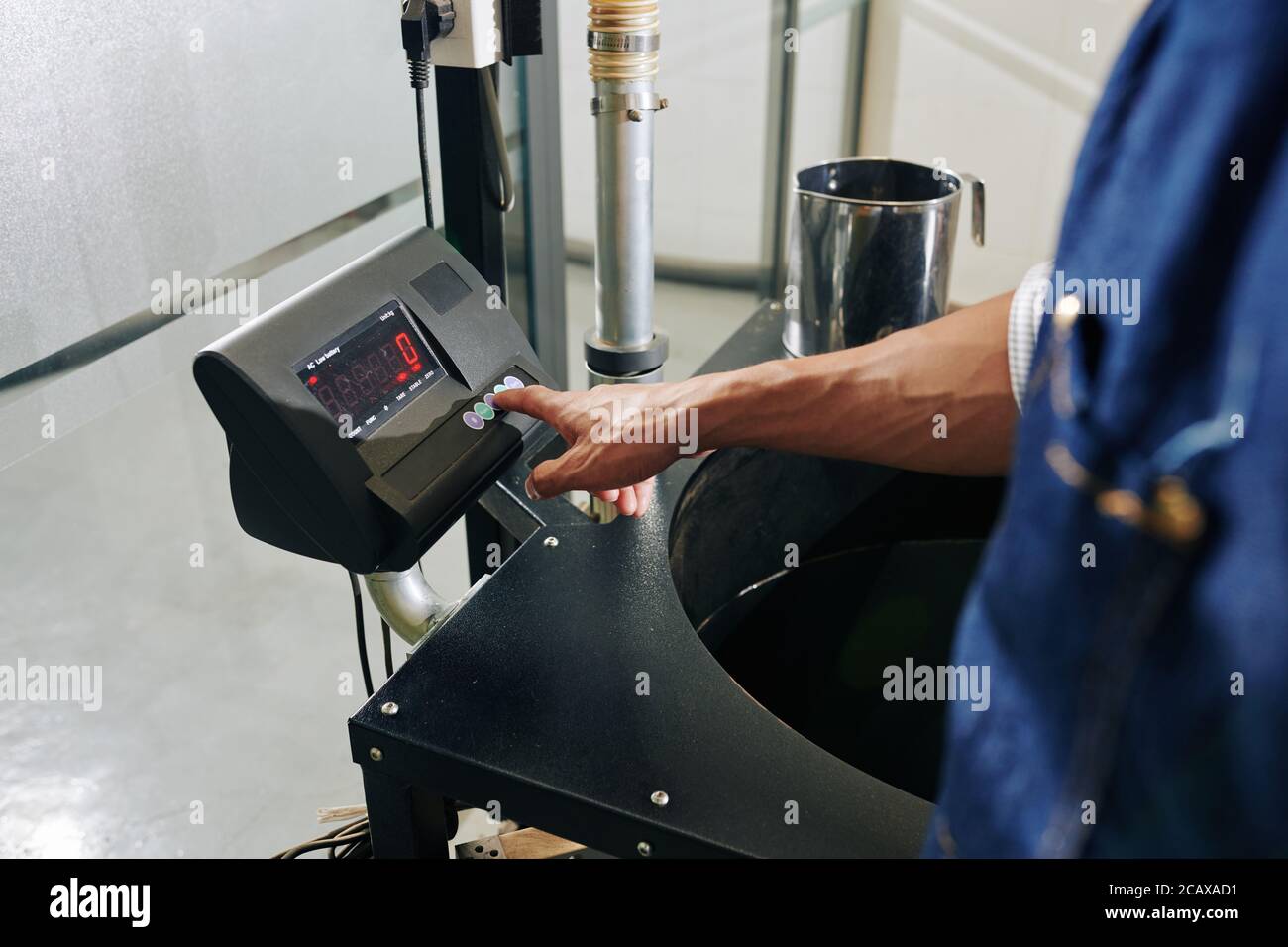 Hands of worker pushing button on control panel to start work of coffee ...