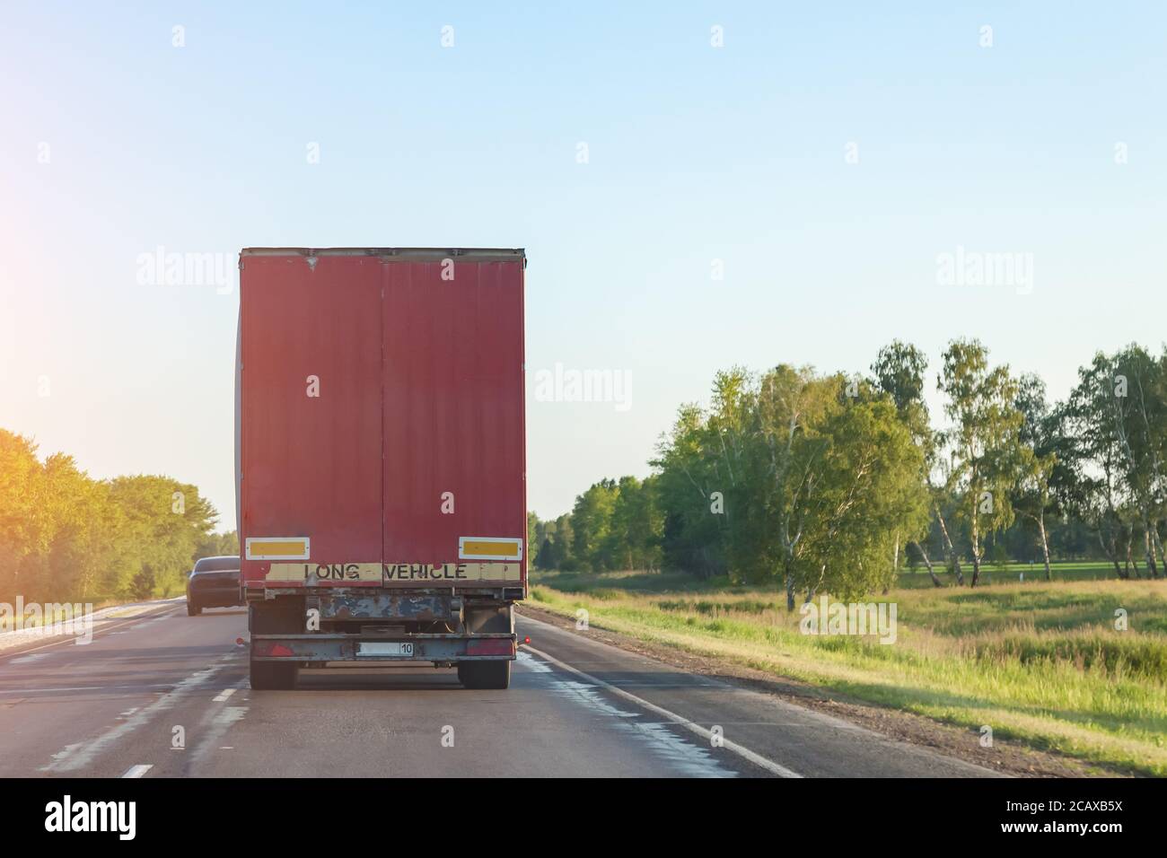 Rear view of a truck with a red body on a road, delivering and ...