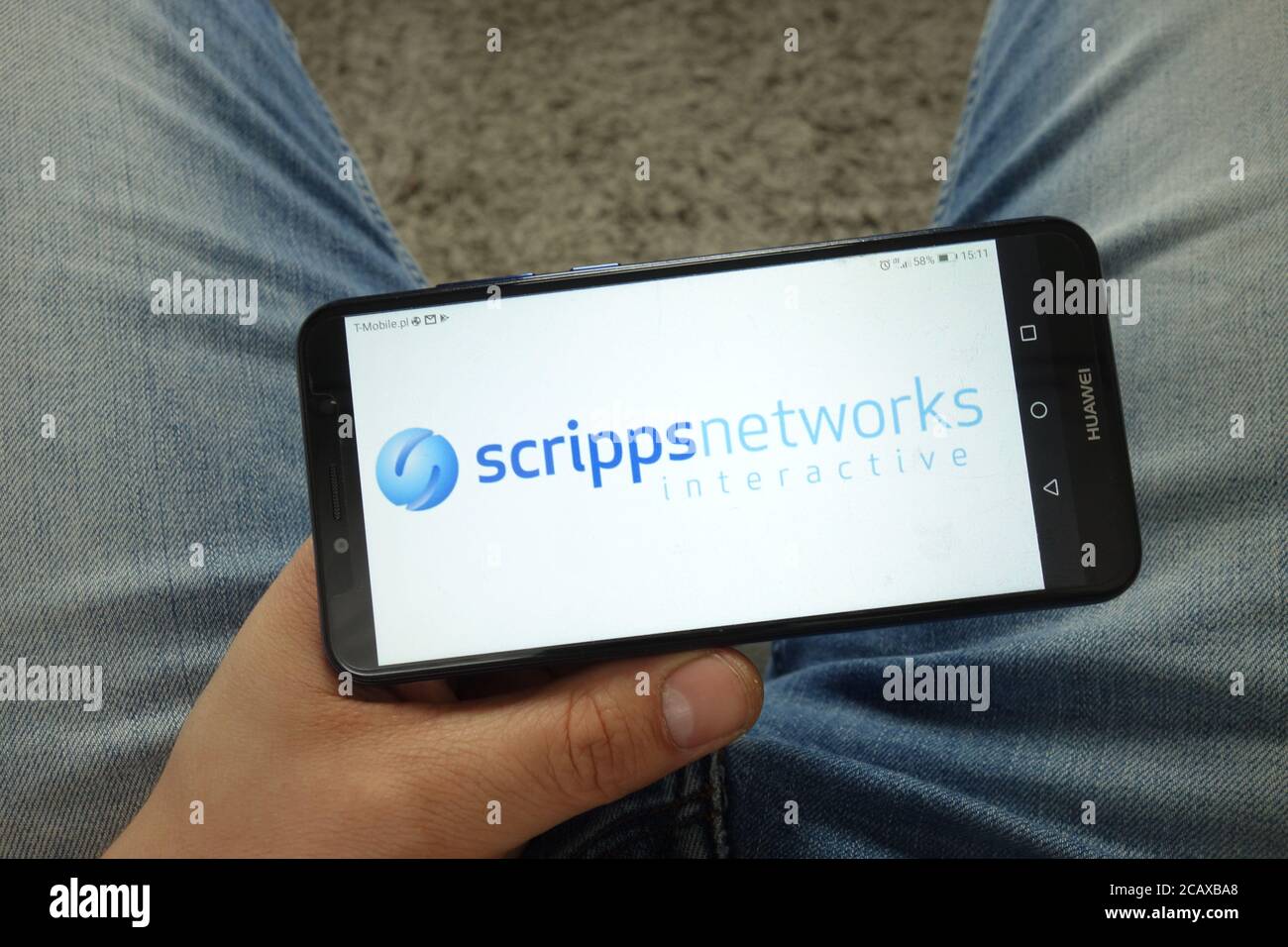 Man holding smartphone with Scripps Networks Interactive company logo ...