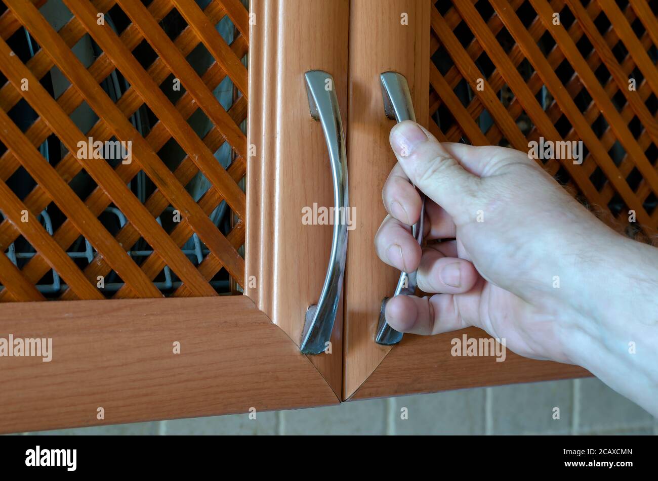 Male hand opens a kitchen cabinet. Wooden kitchen cabinet door. Life ...