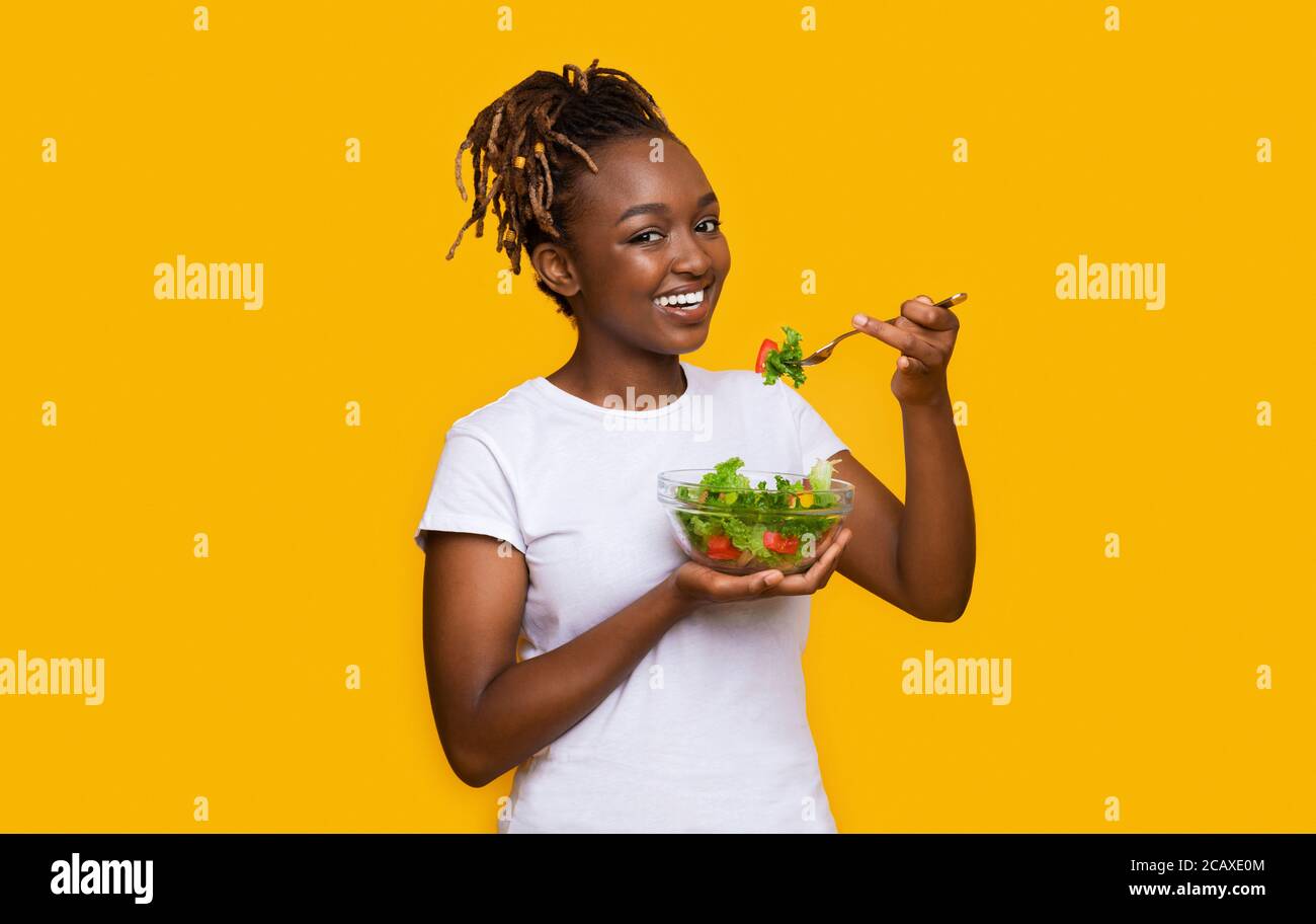 Healthy african woman eating fresh salad over yellow Stock Photo - Alamy