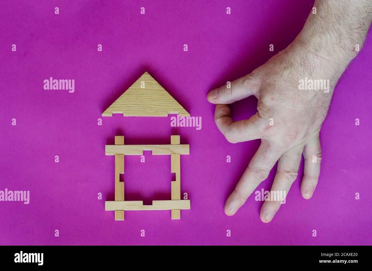 Male hand shares click with sticks on the roof of toy children wooden ...