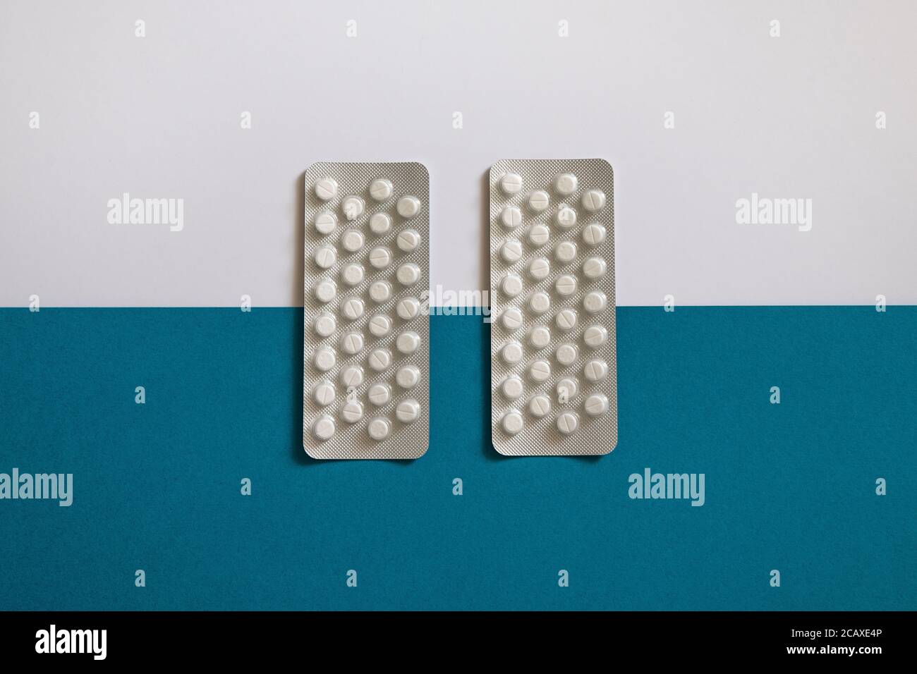Two strips of oral contraceptive pills laying flat against blue and ...