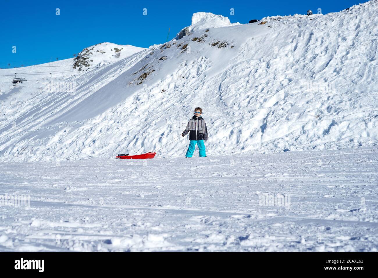 Boy with red sled in snow. Snow mountain background. Winter holidays ...