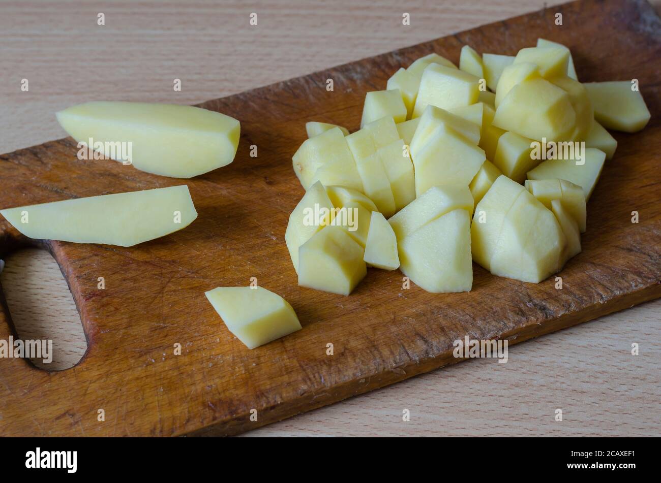 Serving of diced raw potatoes on wooden cutting board. Cooking process ...