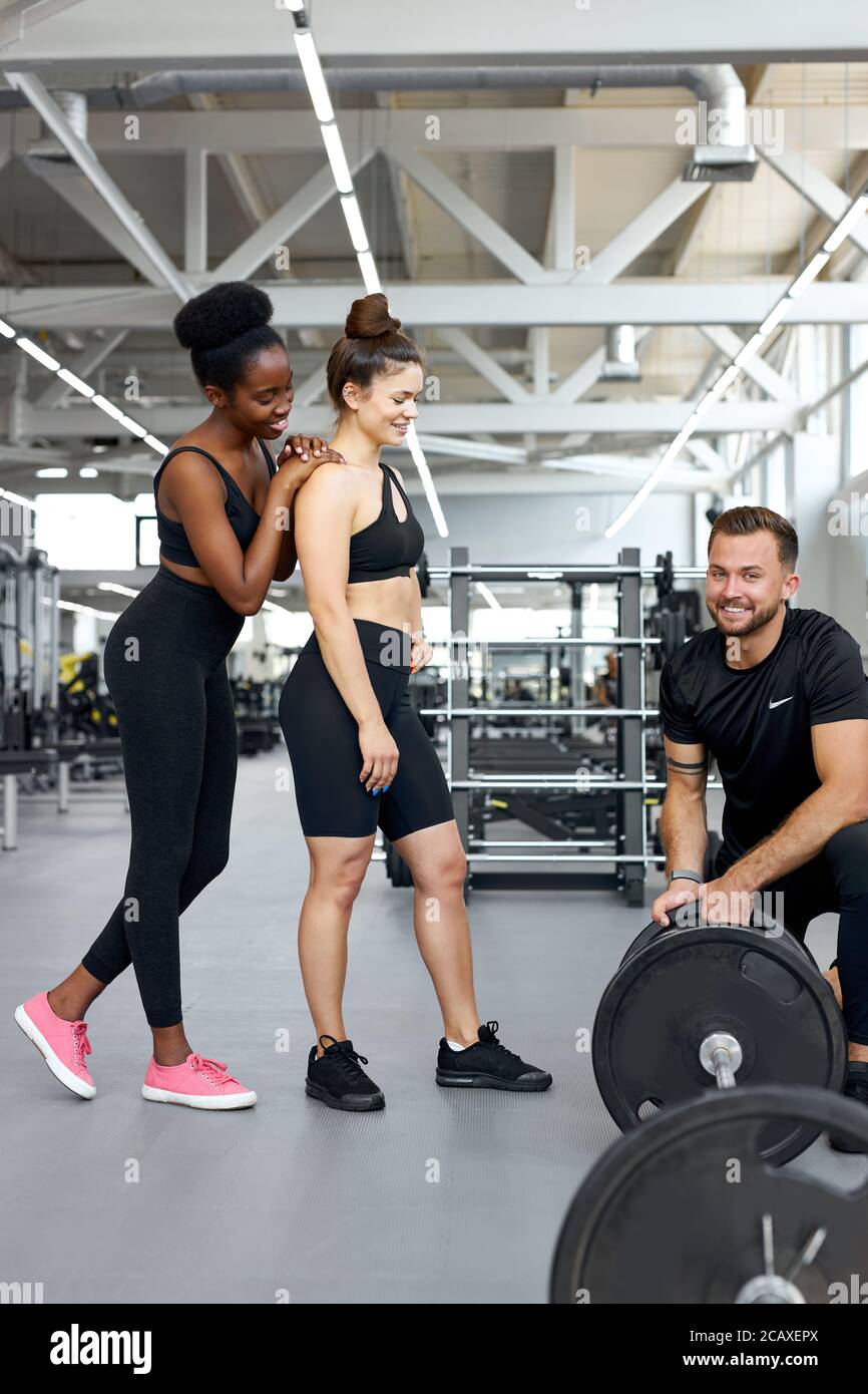 two fit girls training with personal trainer in gym, man teach ...