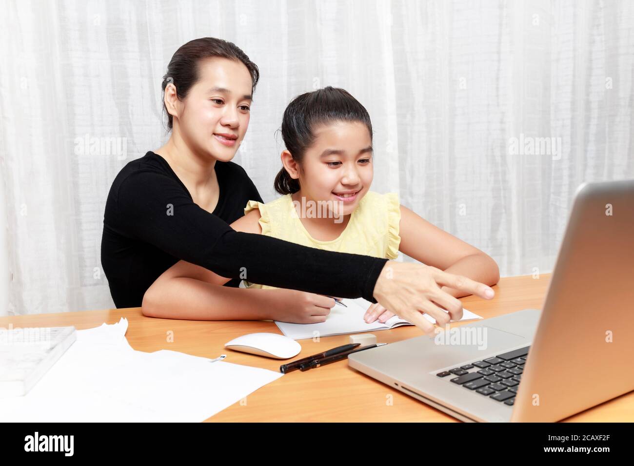 Asian young little girl using pencil to do homework with her mother ...
