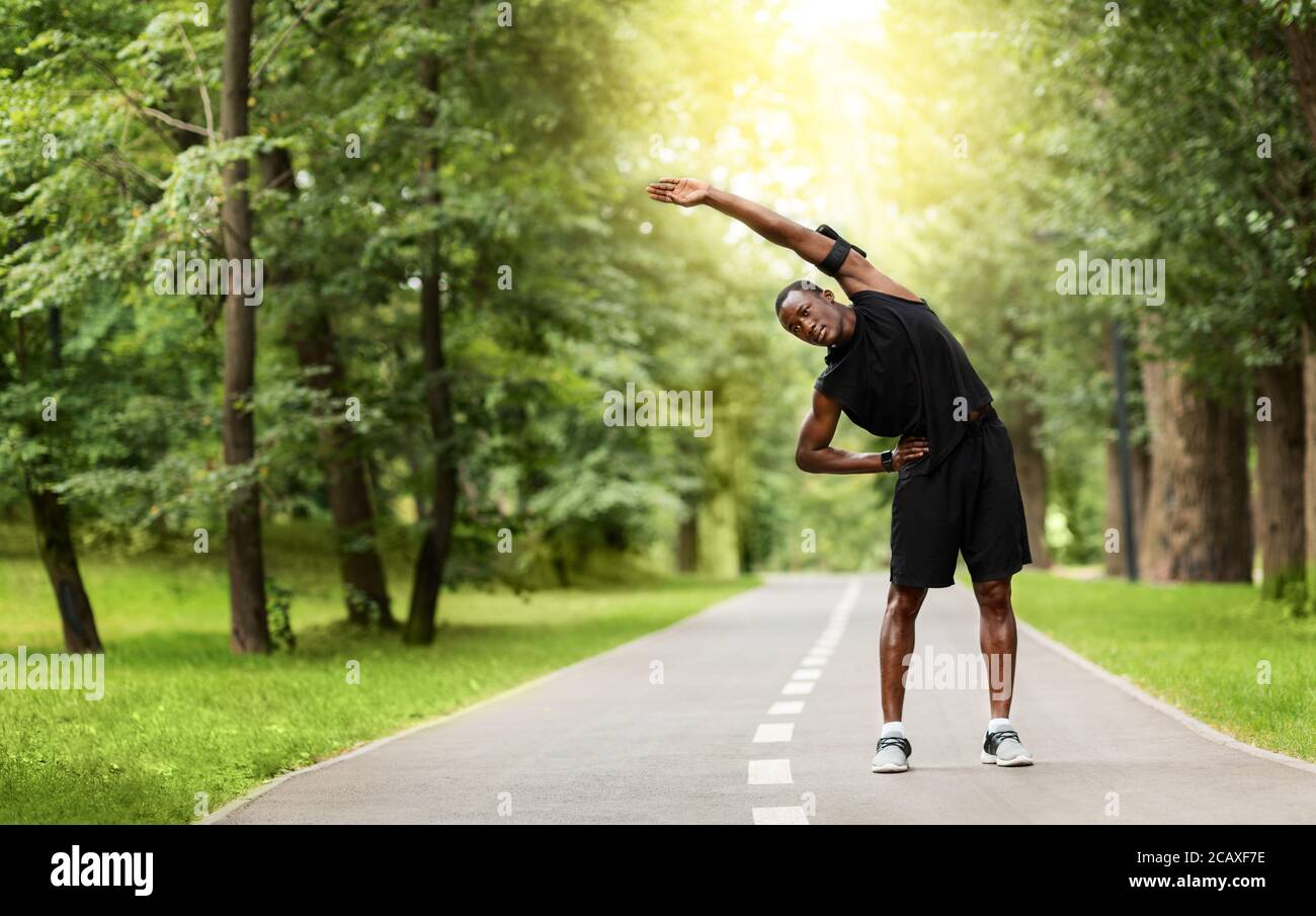 Flexible african sportsman stretching in public park Stock Photo - Alamy