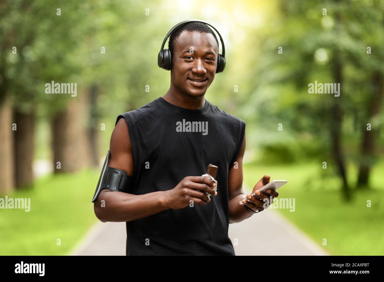 Smiling black guy sportsman eating protein bar while having break Stock ...