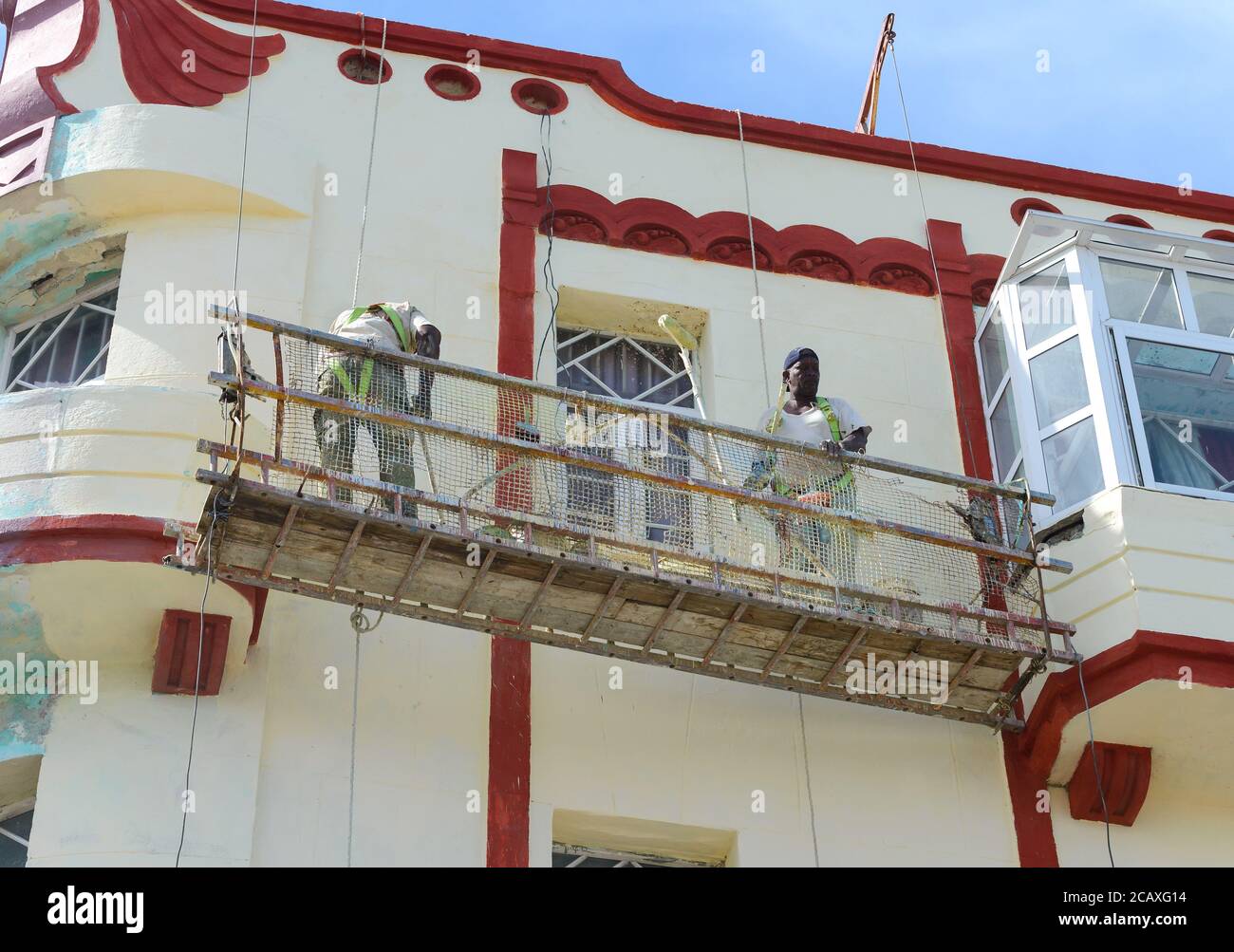 Two cuban construction painters on a scaffolding working on a building ...