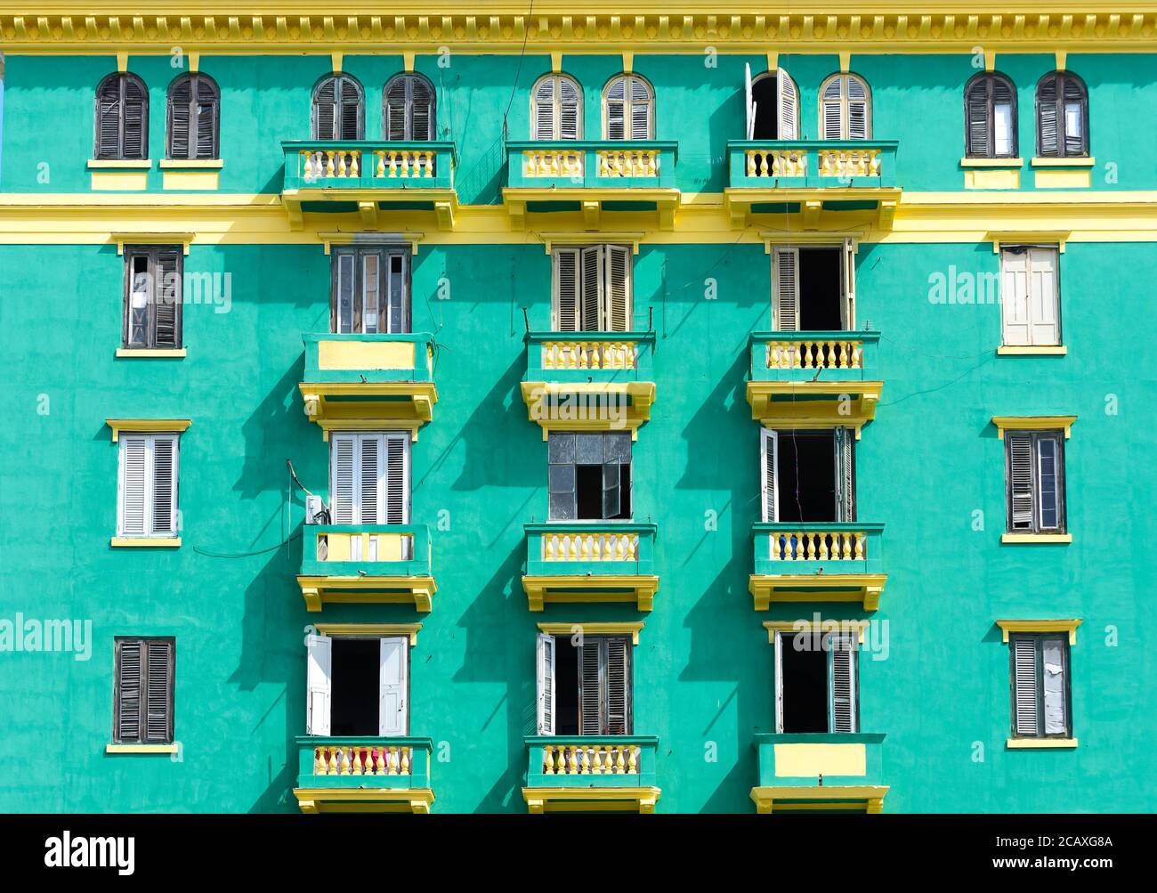 Symmetrical view of green and yellow building with windows and ...