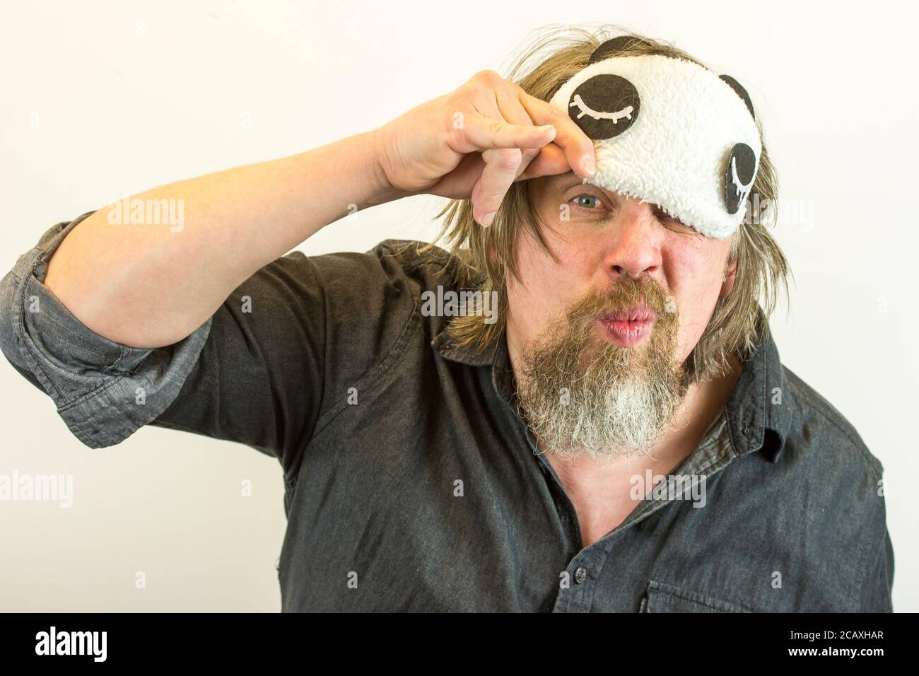 Man with a beard takes off his sleep mask. Upset tired man has not ...