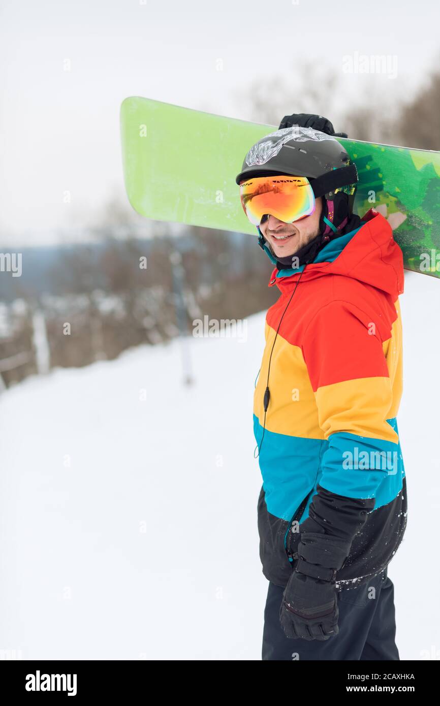 awesome young sportsman has finished snowboarding, side view close up ...