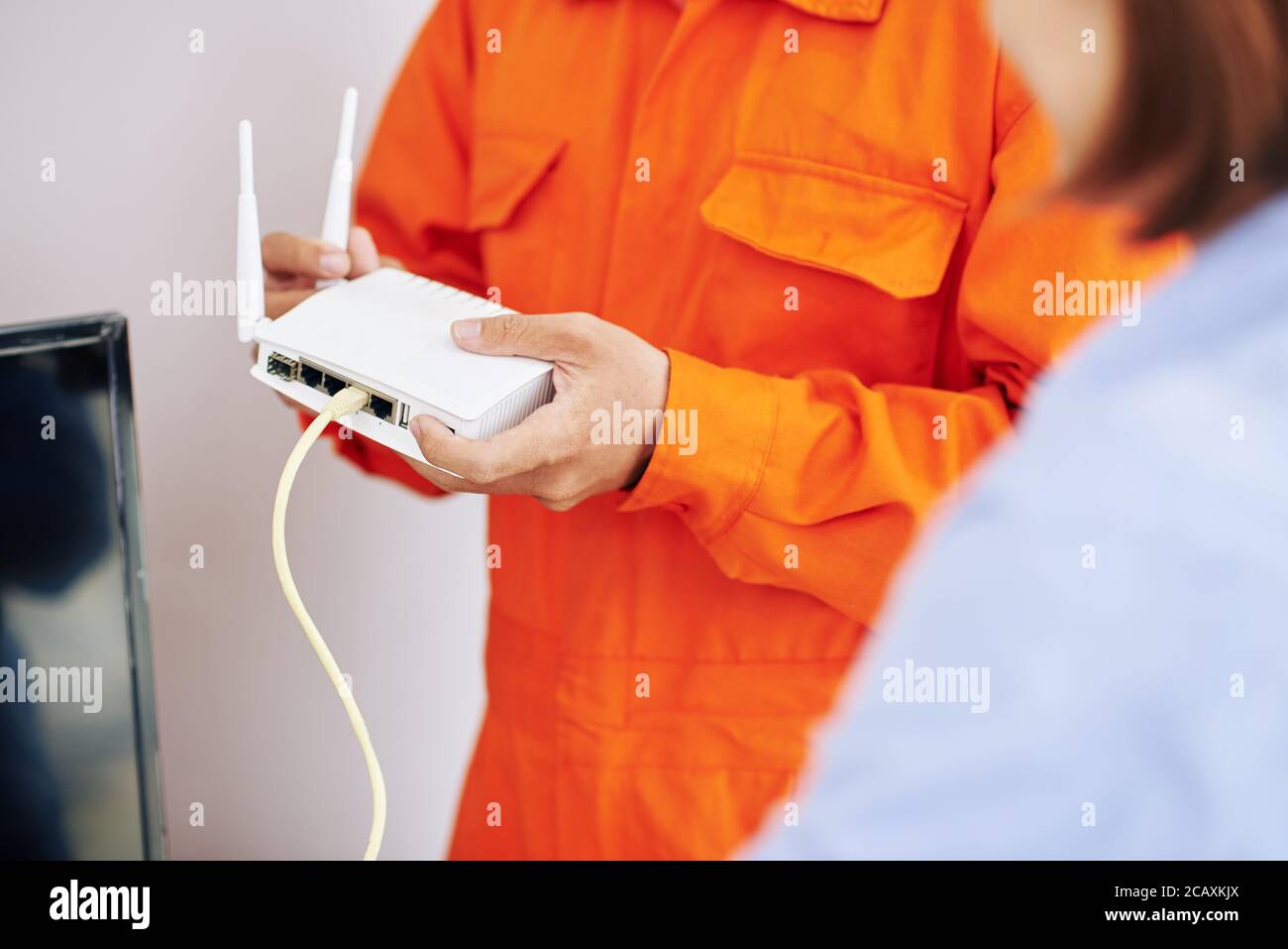Close-up image of electrician explaining woman how to use wi-fi router ...
