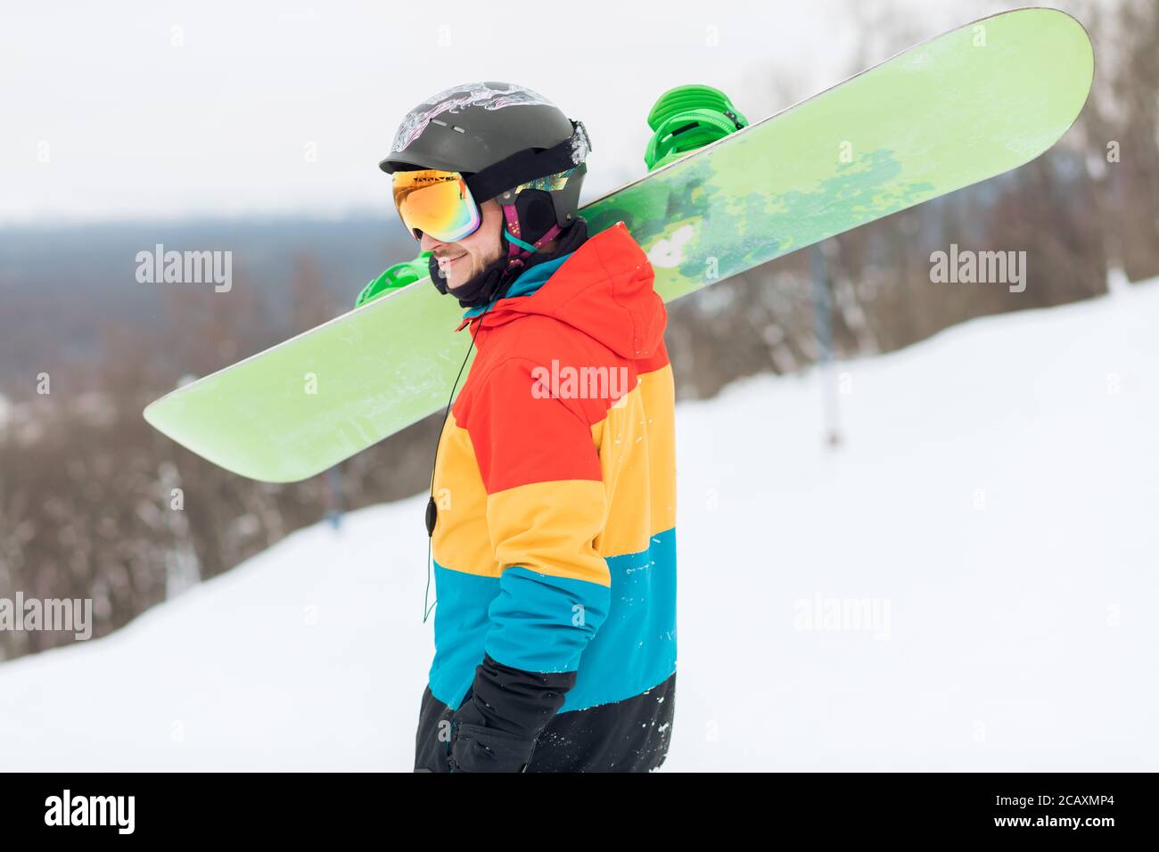 side view photo. sporty cheerful young man with a snowboard going for a ...