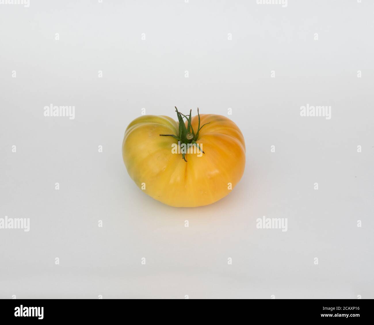 A yellow heirloom tomato isolated in white background Stock Photo - Alamy