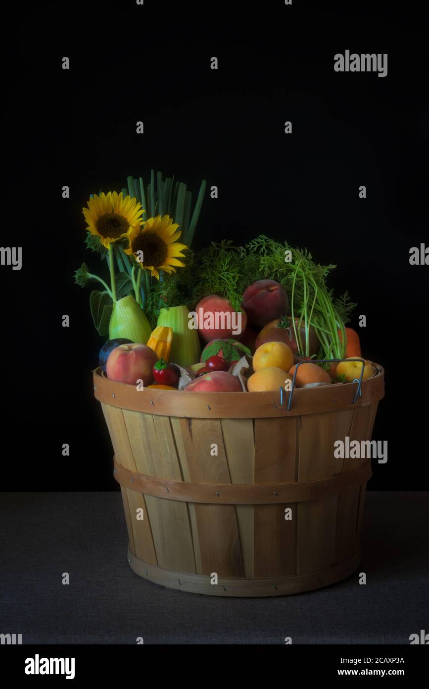 Basket with assorted fruit and vegetables against black background ...