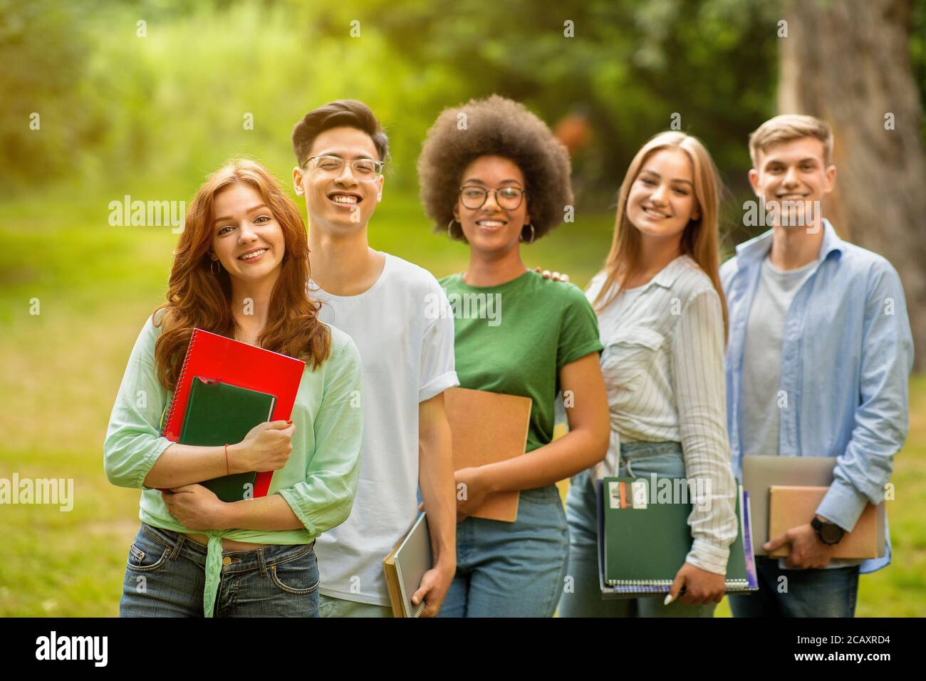 Group portrait of multiracial university students posing with workbooks ...
