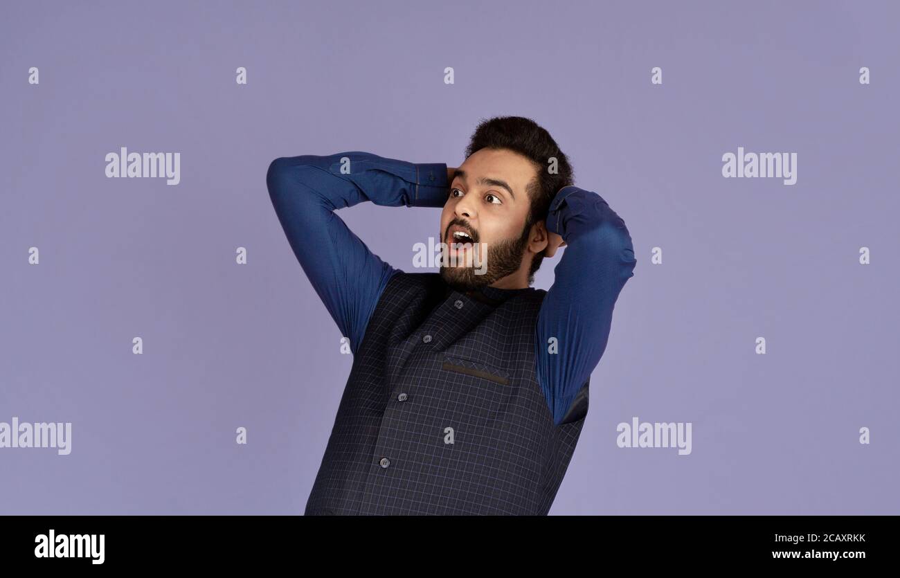Shocked Indian guy holding his head and screaming WOW on violet studio ...