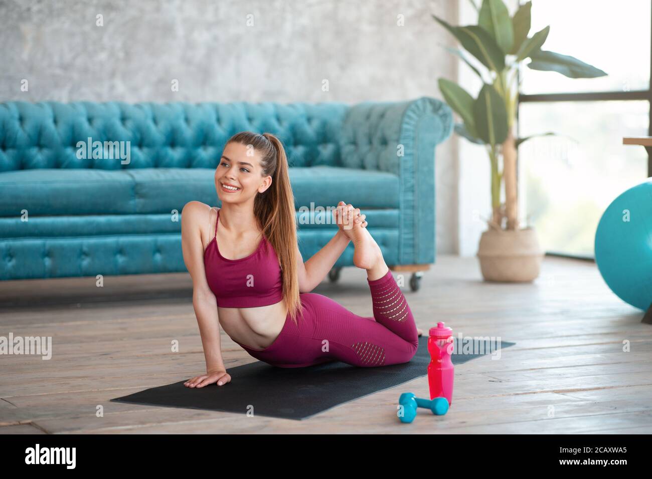 Flexible young girl stretching her leg on yoga mat at home Stock Photo ...