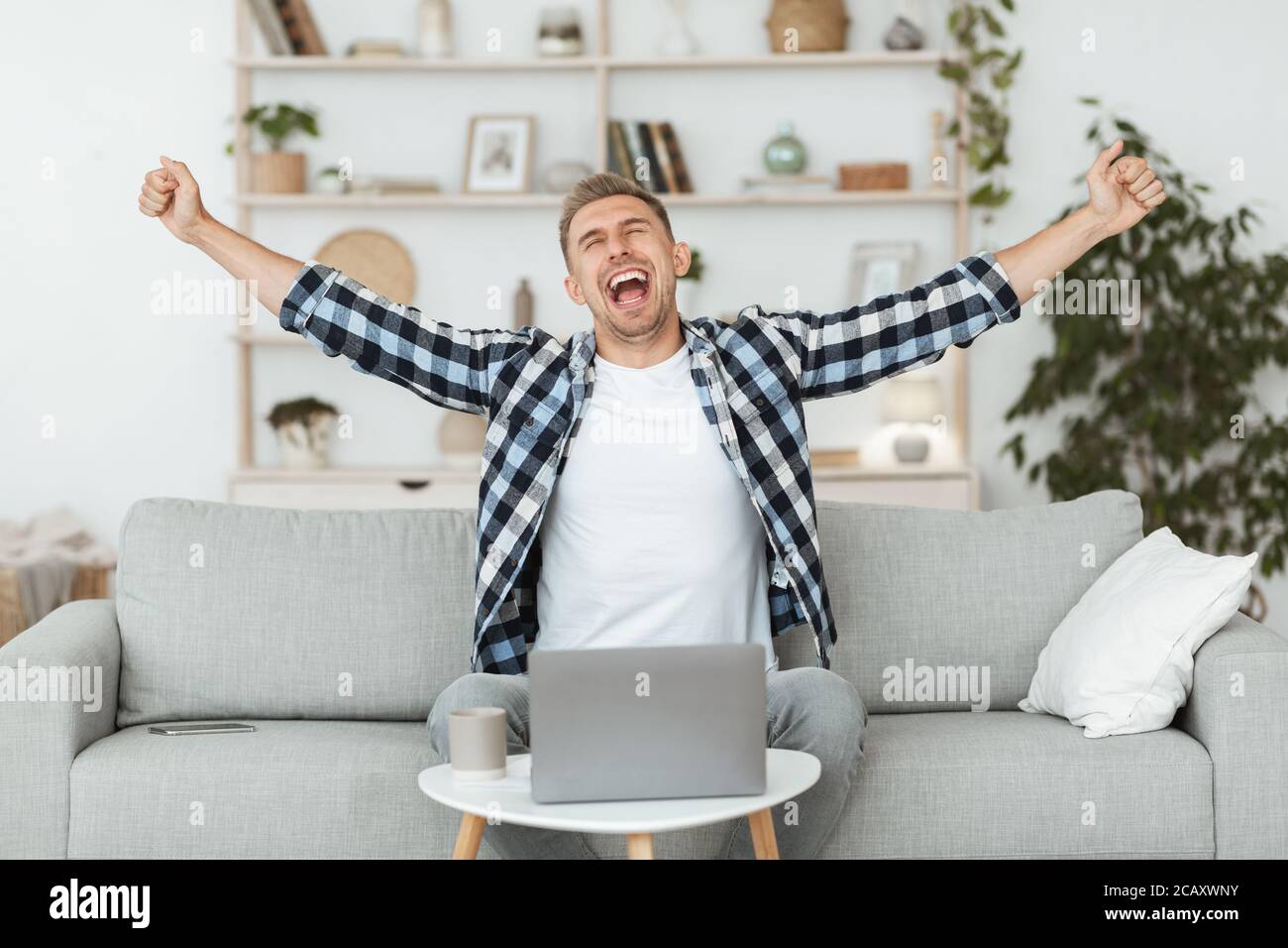 Excited young man feeling ecstatic using computer Stock Photo - Alamy