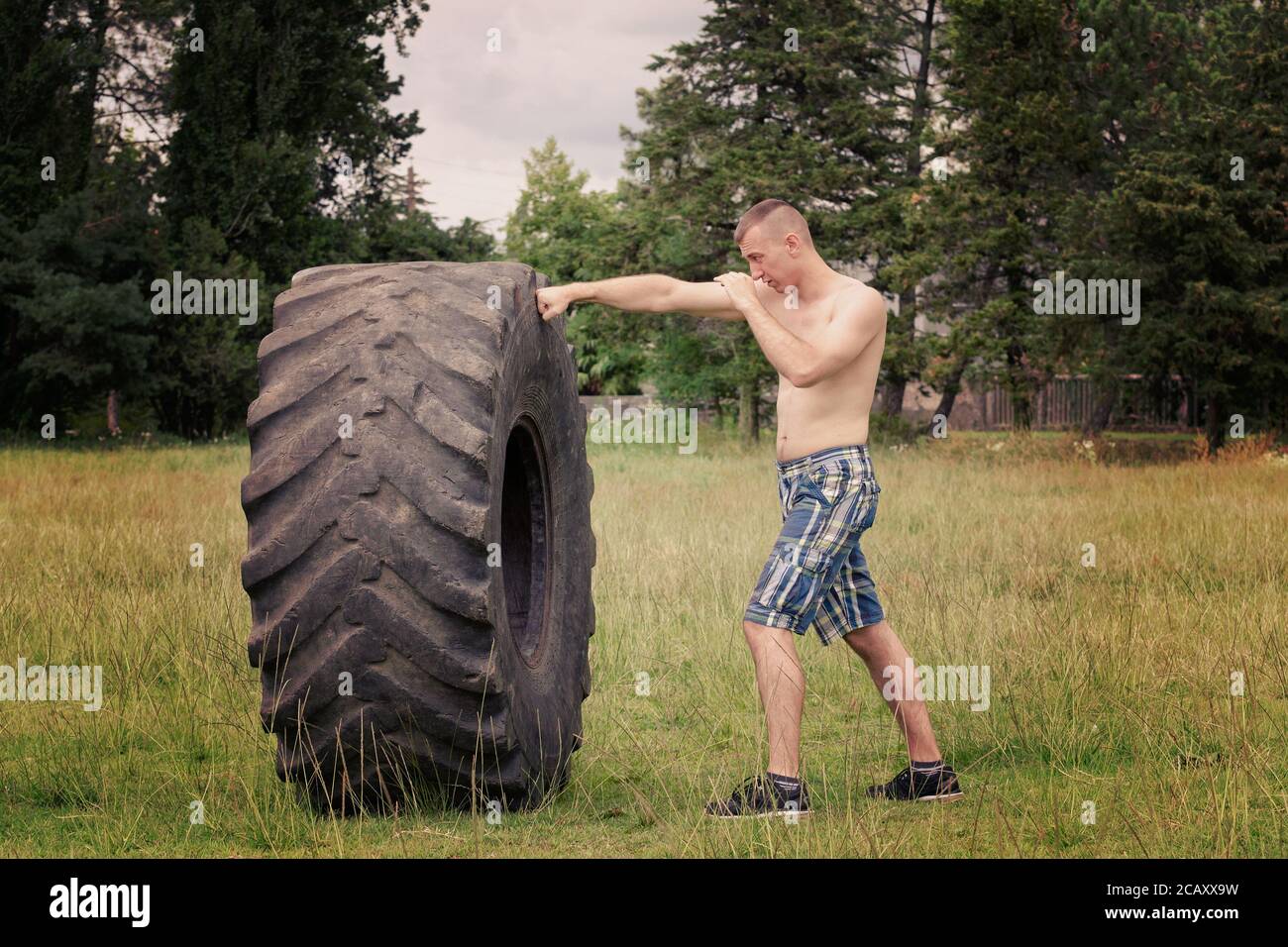 Young man boxing with the tire. Workout Stock Photo - Alamy