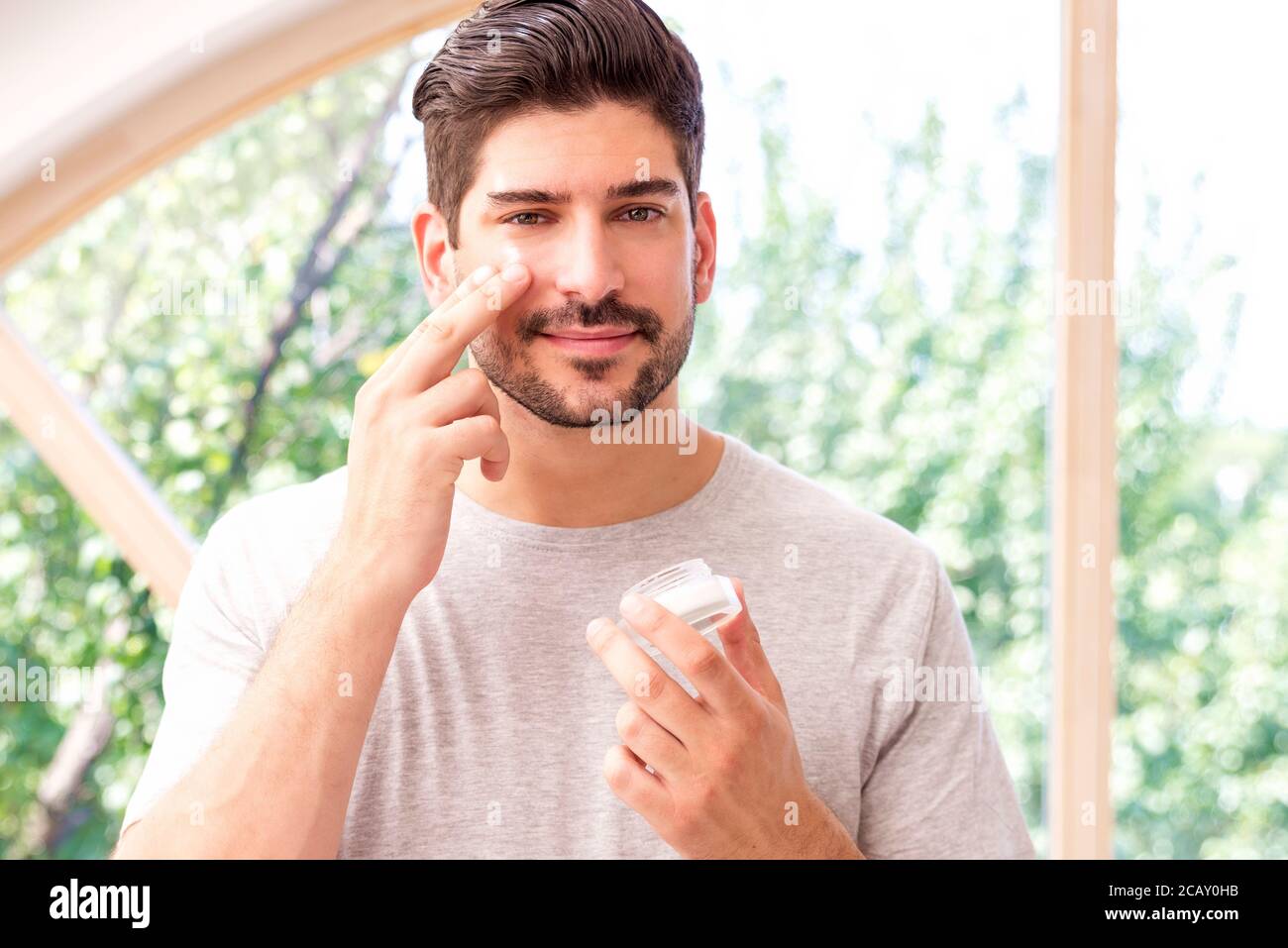 Shot of handsome man applying skincare facial treatment cream on face ...