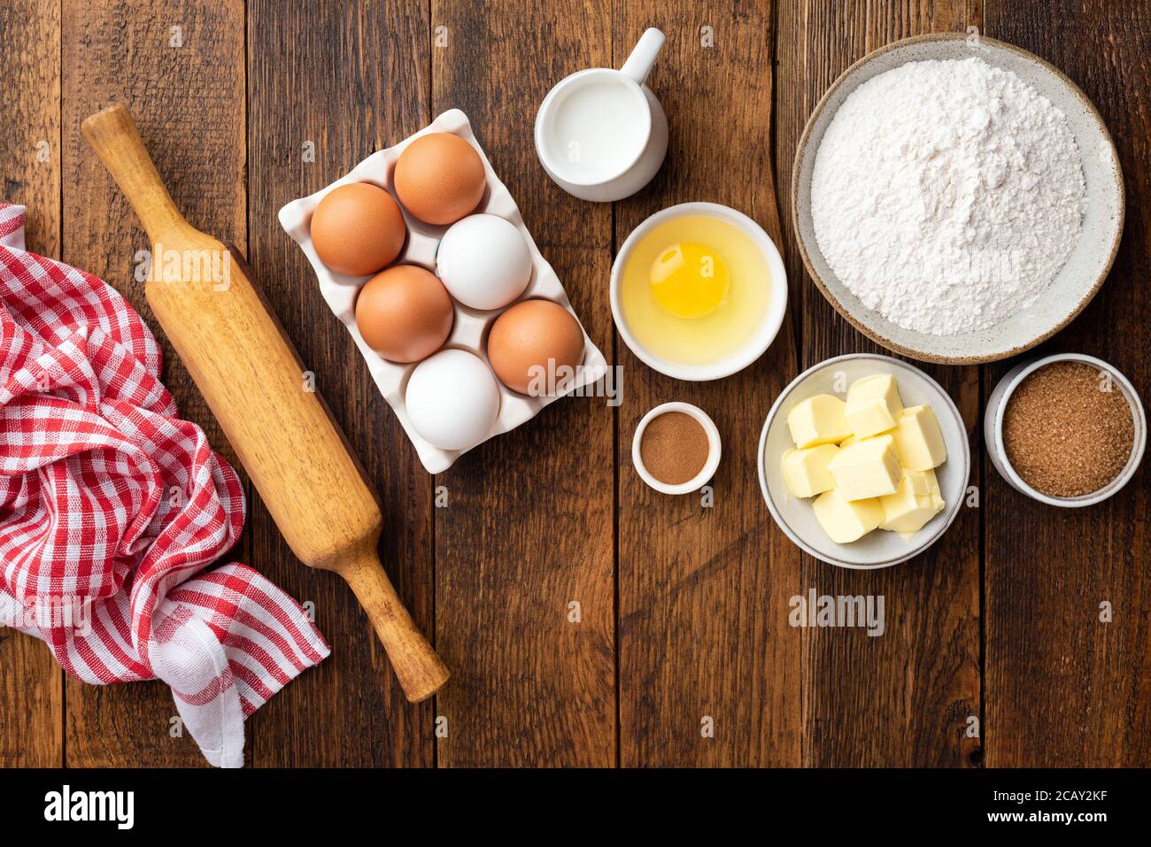 Baking ingredients on a wooden table. Flour butter eggs sugar and milk ...