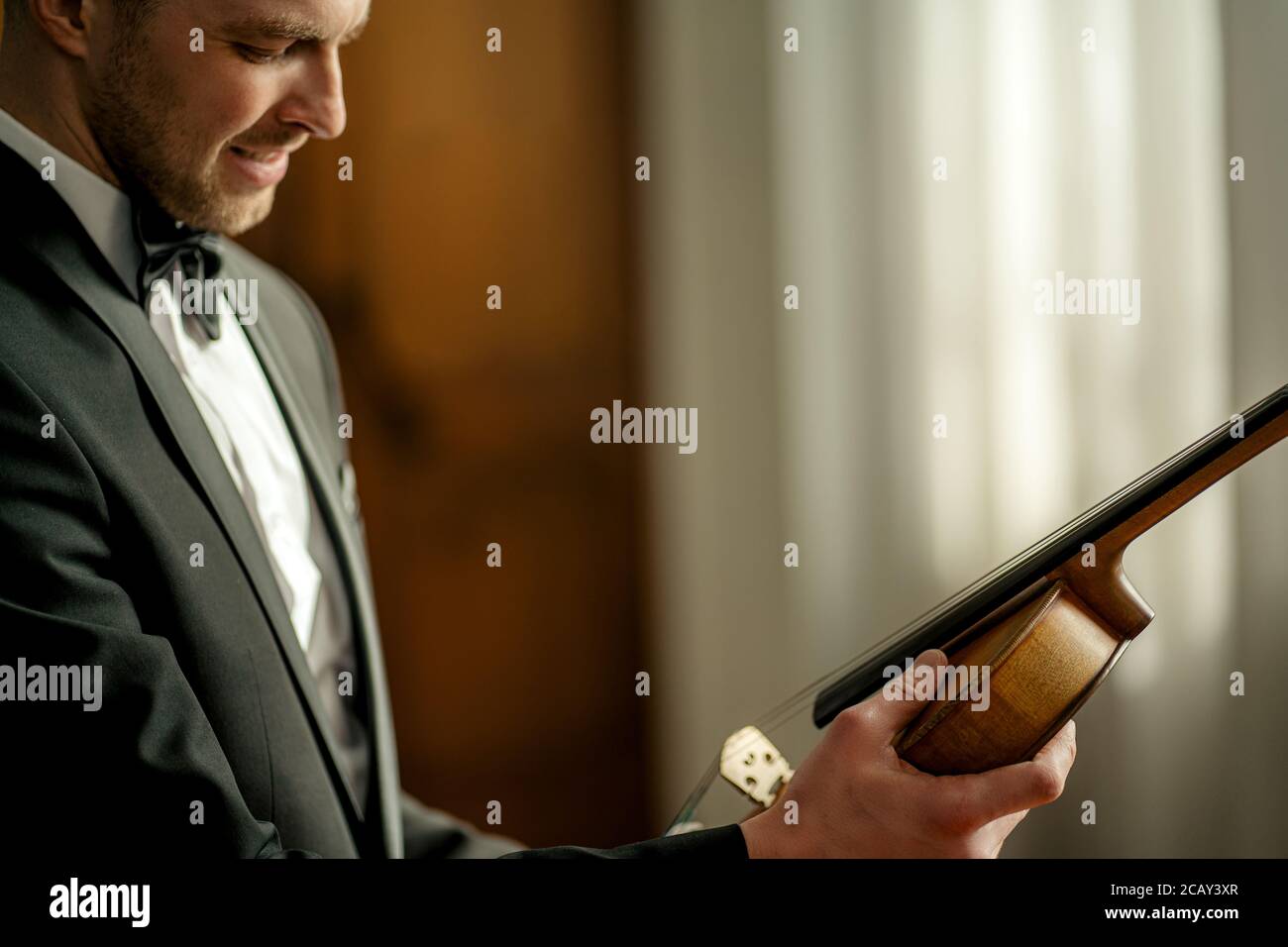 professional talented caucasian male violinist look at his instrument ...