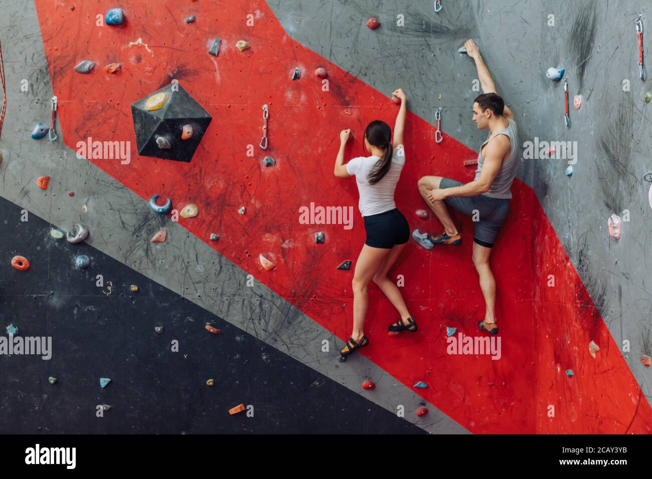 Young woman trying to climb for the first time. Attentive man giving ...