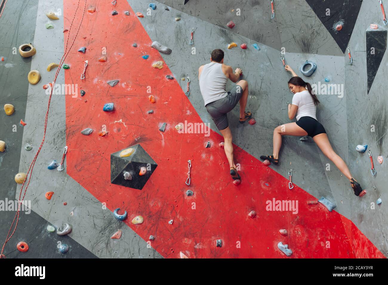 Pretty woman looking down the climbing wall. Scared woman. Strong man ...