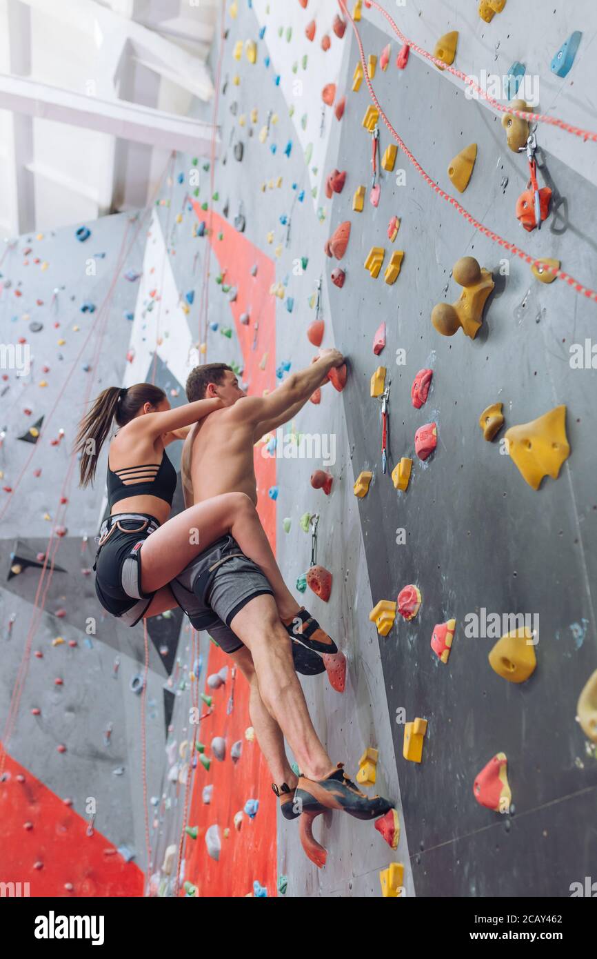 athlete guy carring a woman on his back while climbing in the sport ...