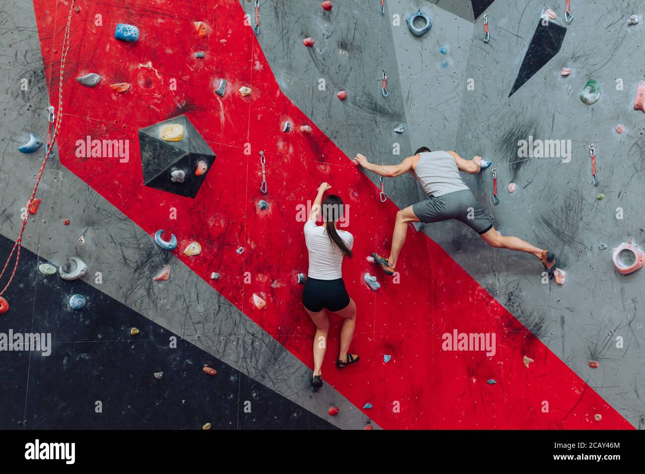 two young fit people are climbing indoors. They like the challenge. The ...