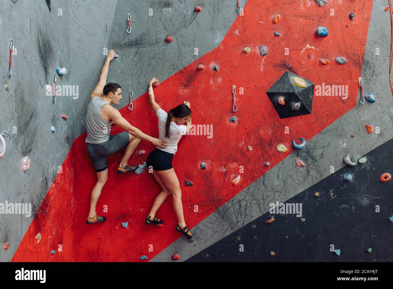 Beatiful woman in bouldering course. Her friend helping her to go ...