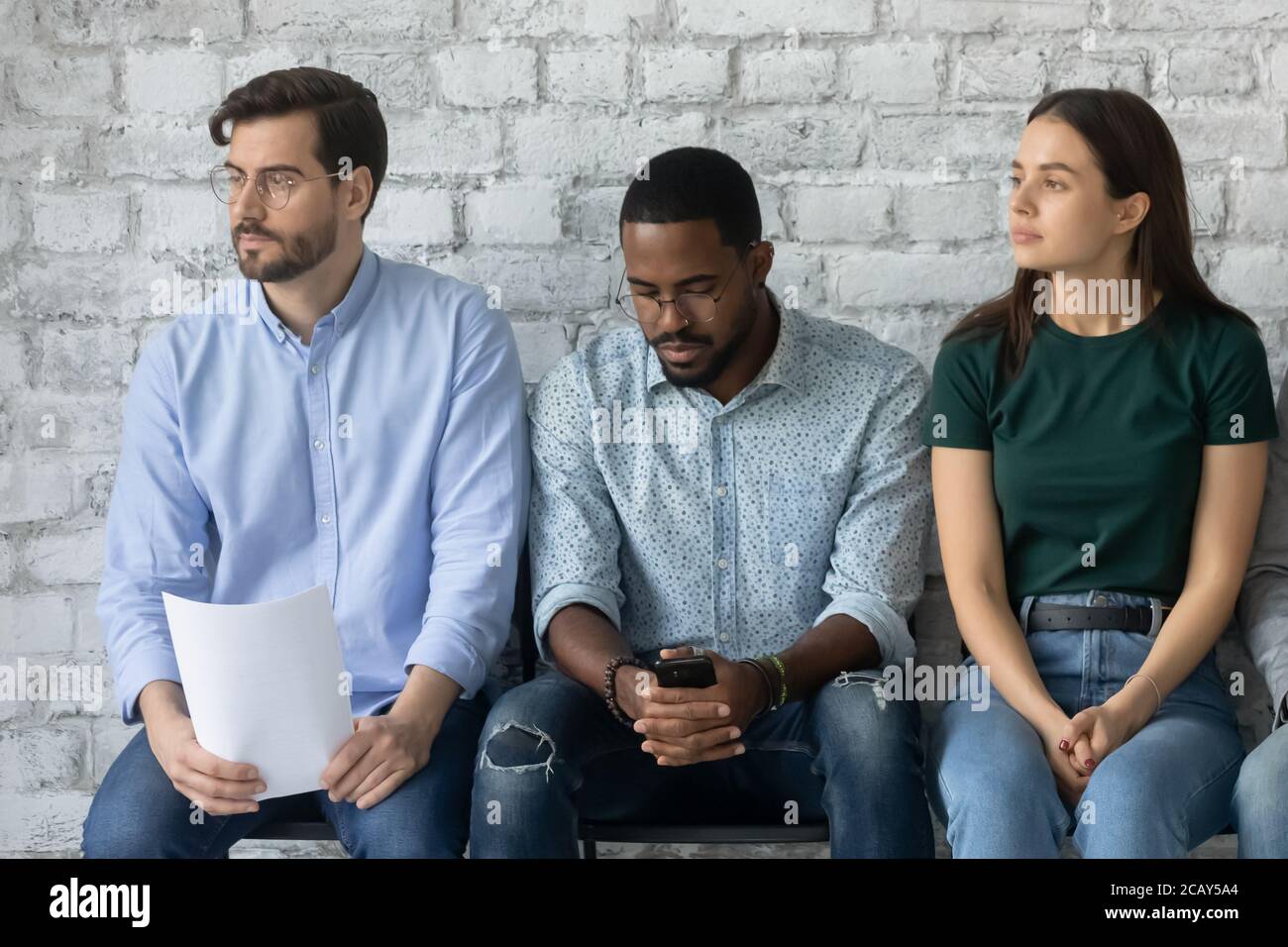 Tired diverse candidates waiting for job interview, sitting in queue ...