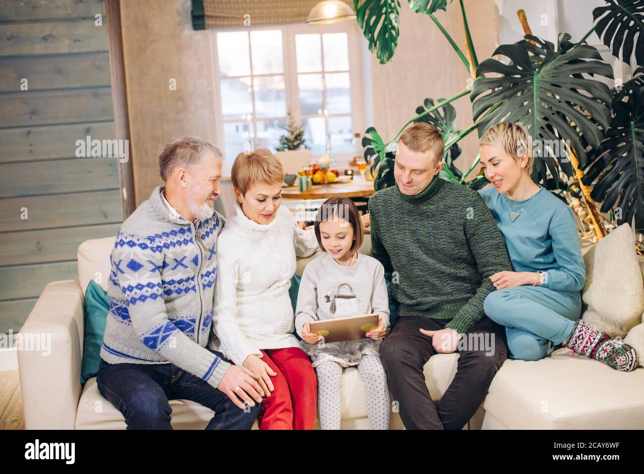 Big family looking at the screen of tablet PC in a living room. family ...