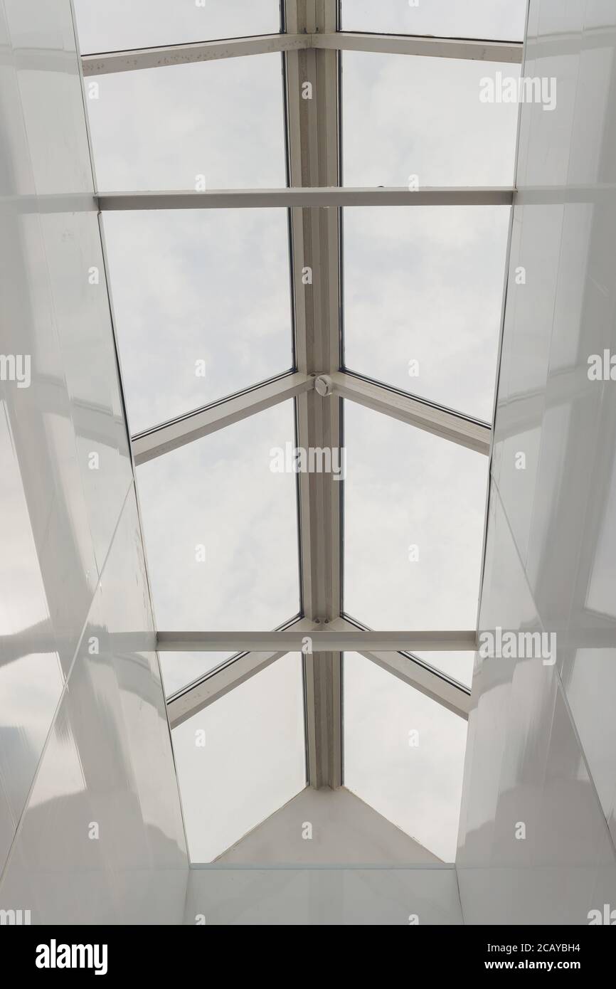 Looking up to the blue cloudy sky through modern square ceiling window ...