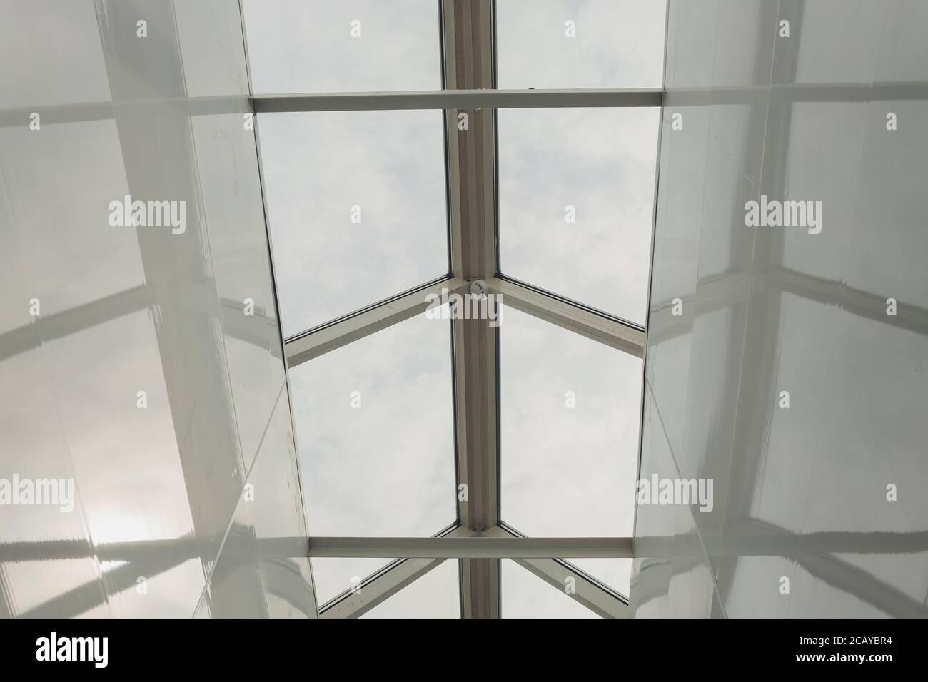 Looking up to the blue cloudy sky through modern square ceiling window ...
