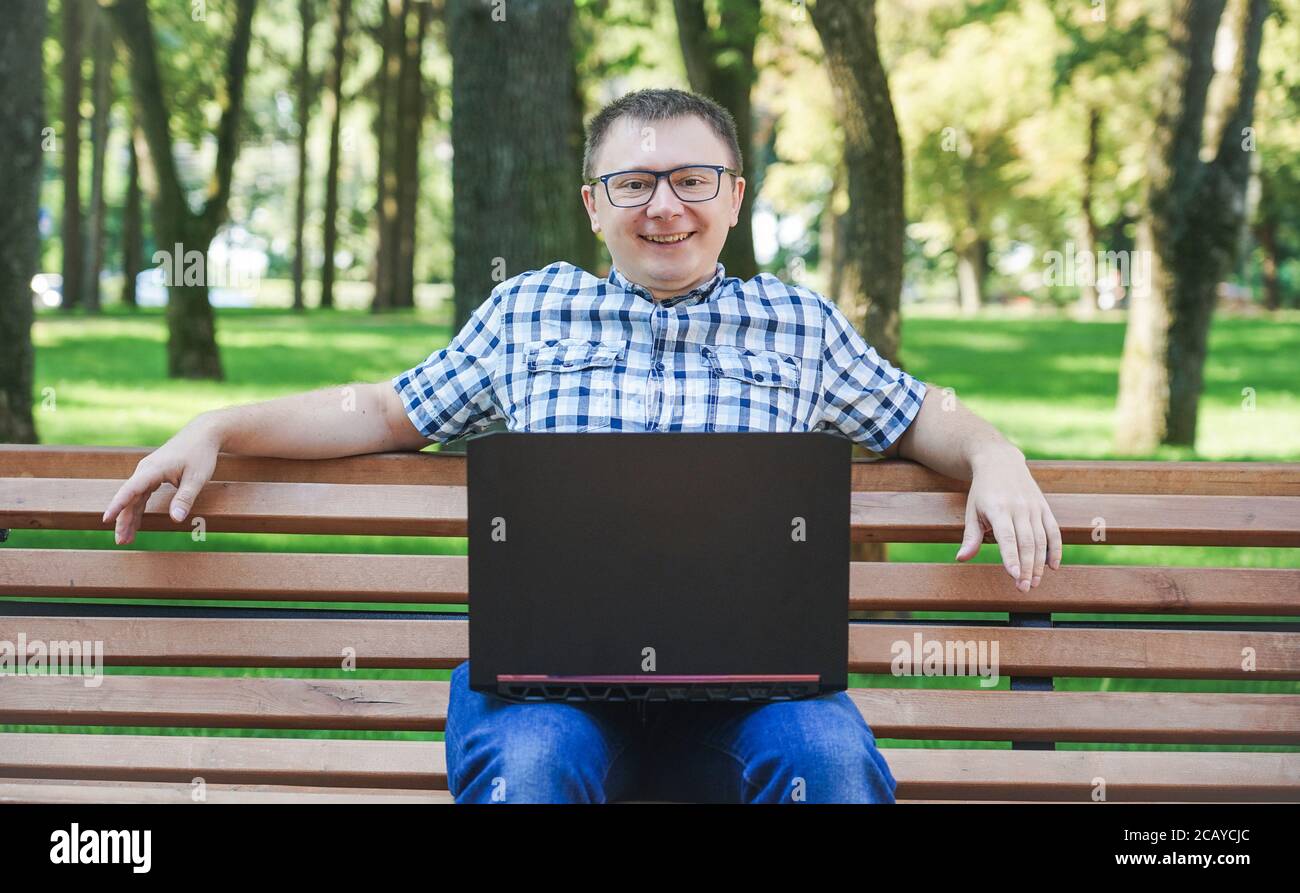 A guy with a laptop sits on a park bench Stock Photo - Alamy