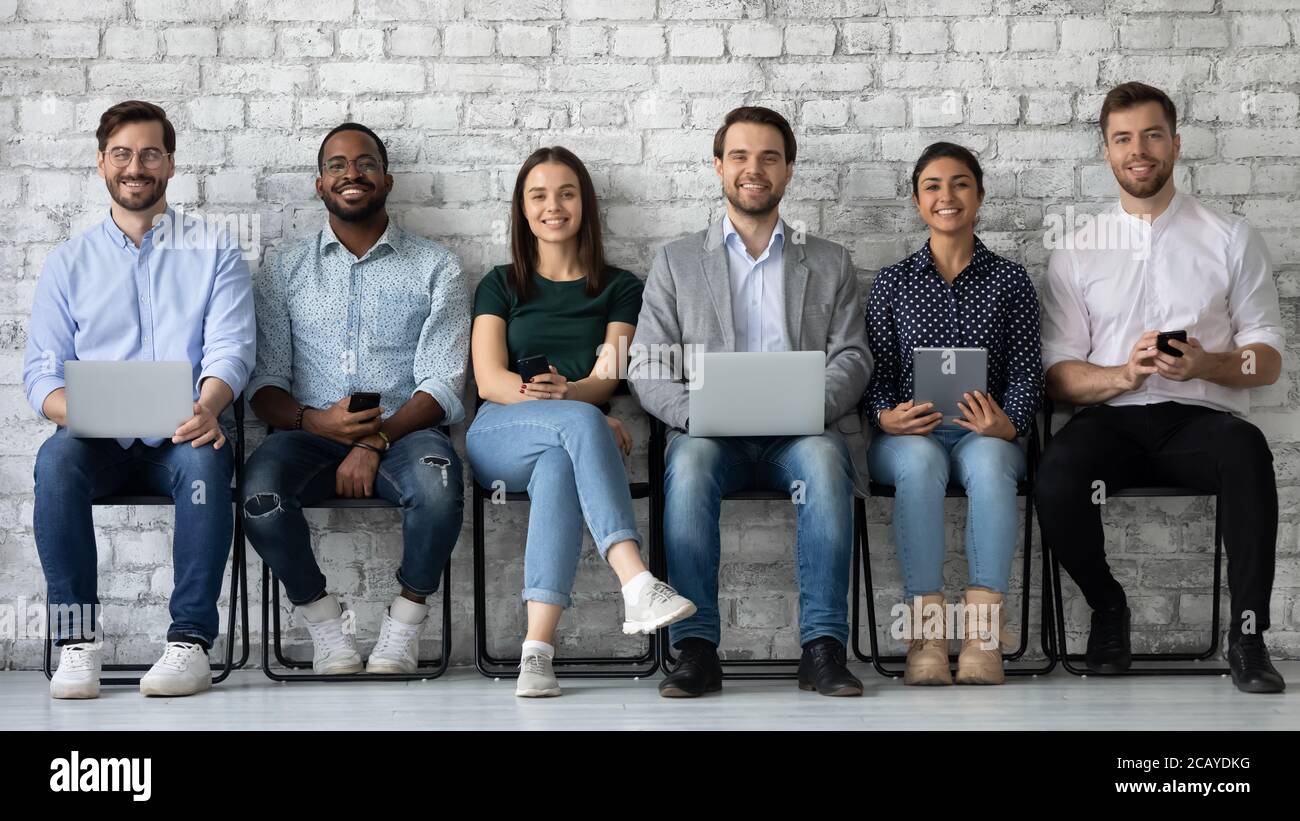 Portrait smiling diverse candidates sitting on chairs in row Stock ...