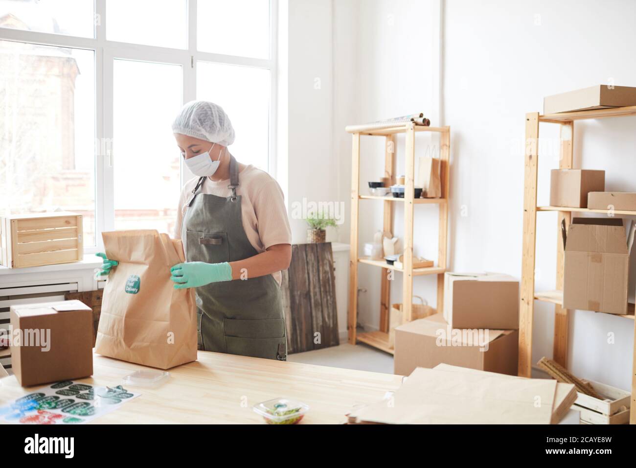 Waist up portrait of female worker wearing protective clothing while ...