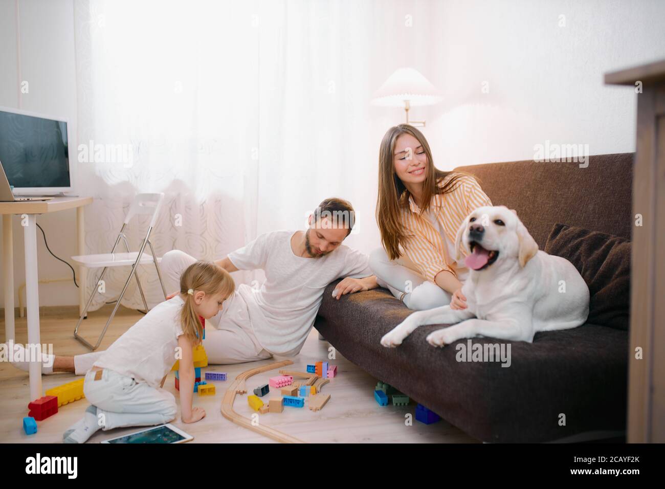 friendly adorable family in living room, playing with domestic pet ...