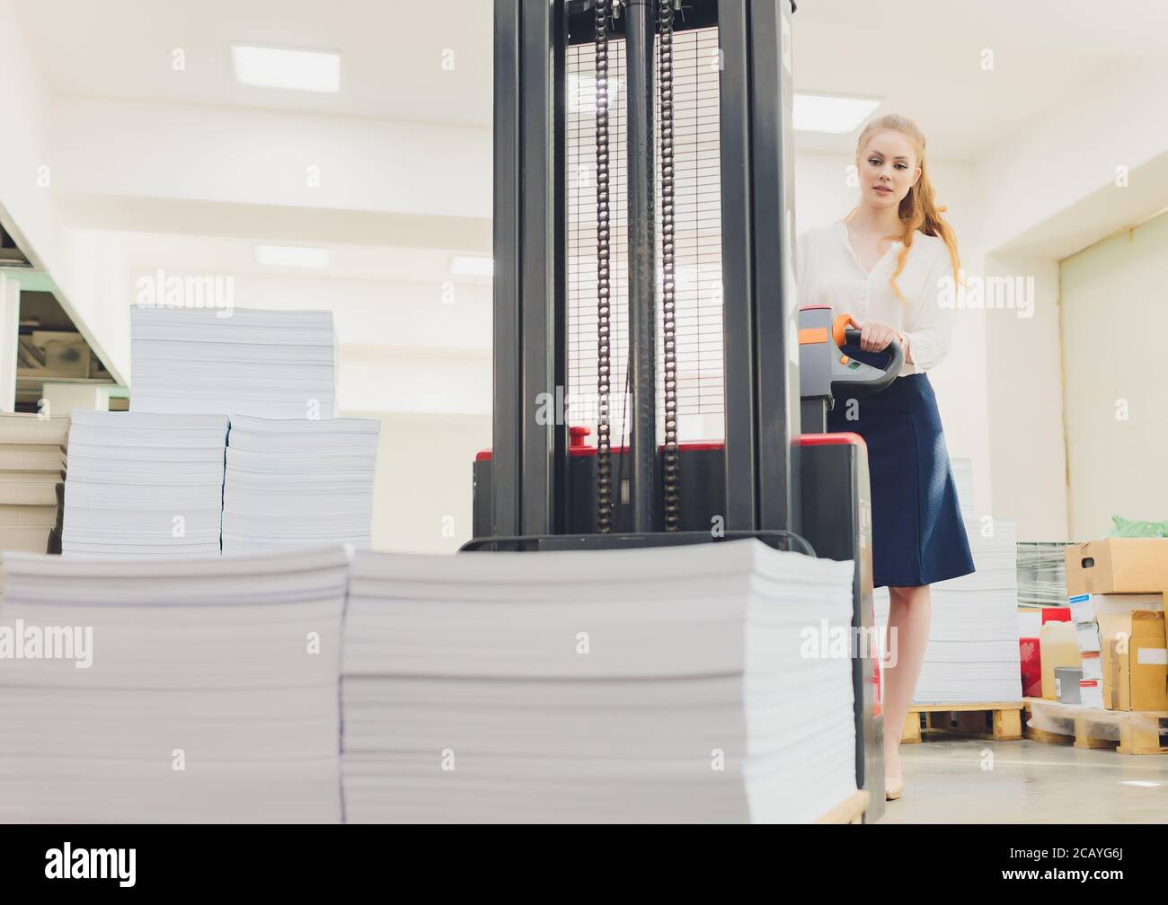 Factory Worker Using Powered Fork Lift To Load Goods. young woman Stock ...