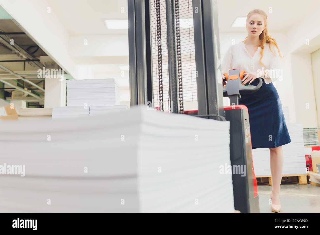 Factory Worker Using Powered Fork Lift To Load Goods. young woman Stock ...