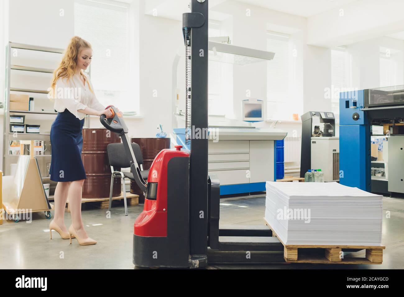 Factory Worker Using Powered Fork Lift To Load Goods. young woman Stock ...
