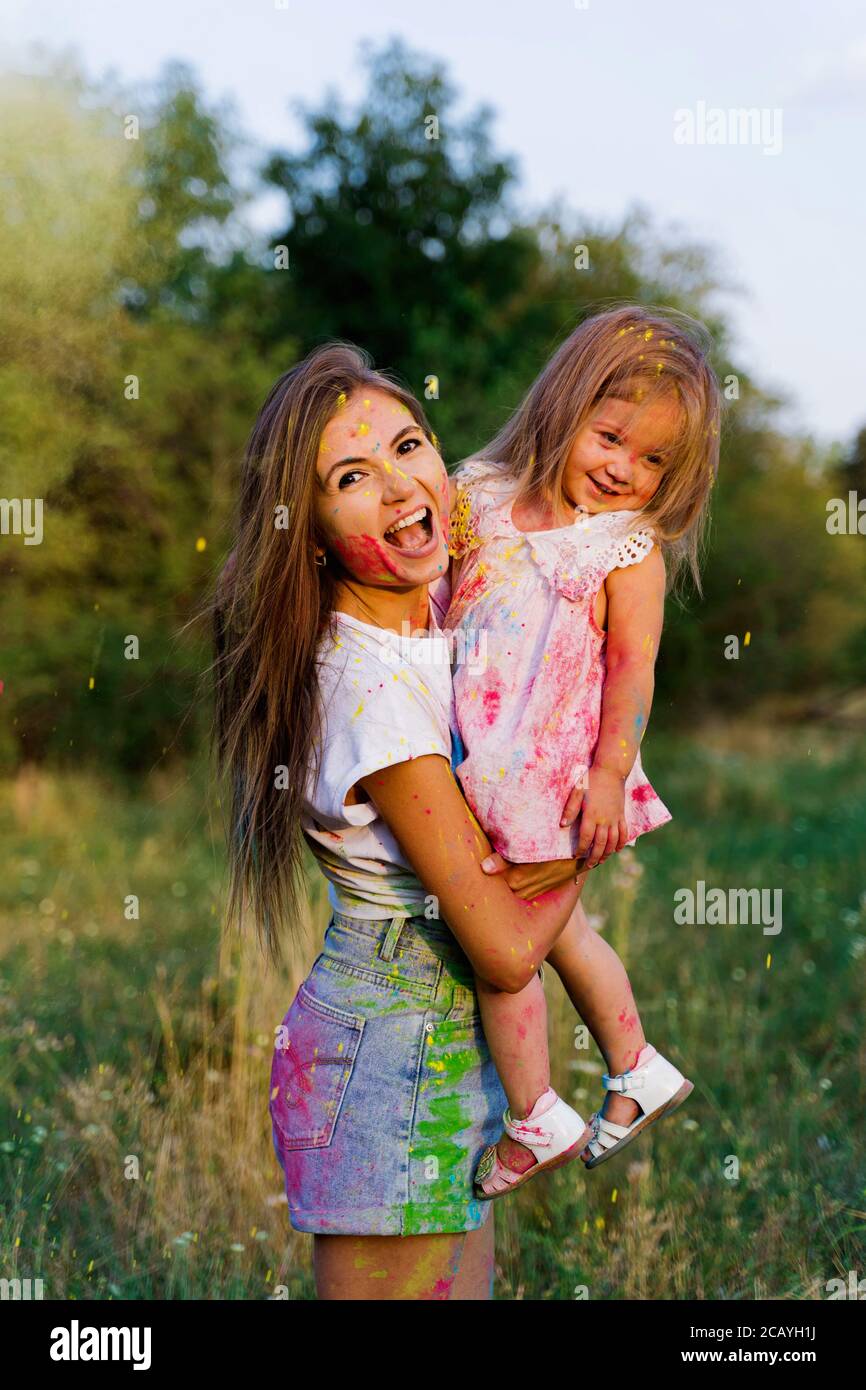 beautiful mom and daughter play with Hol colors. multi-colored paint on ...