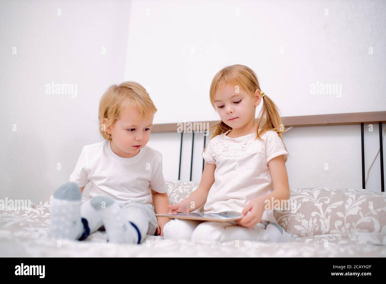 little boy and girl look at screen of laptop, playing or watching ...